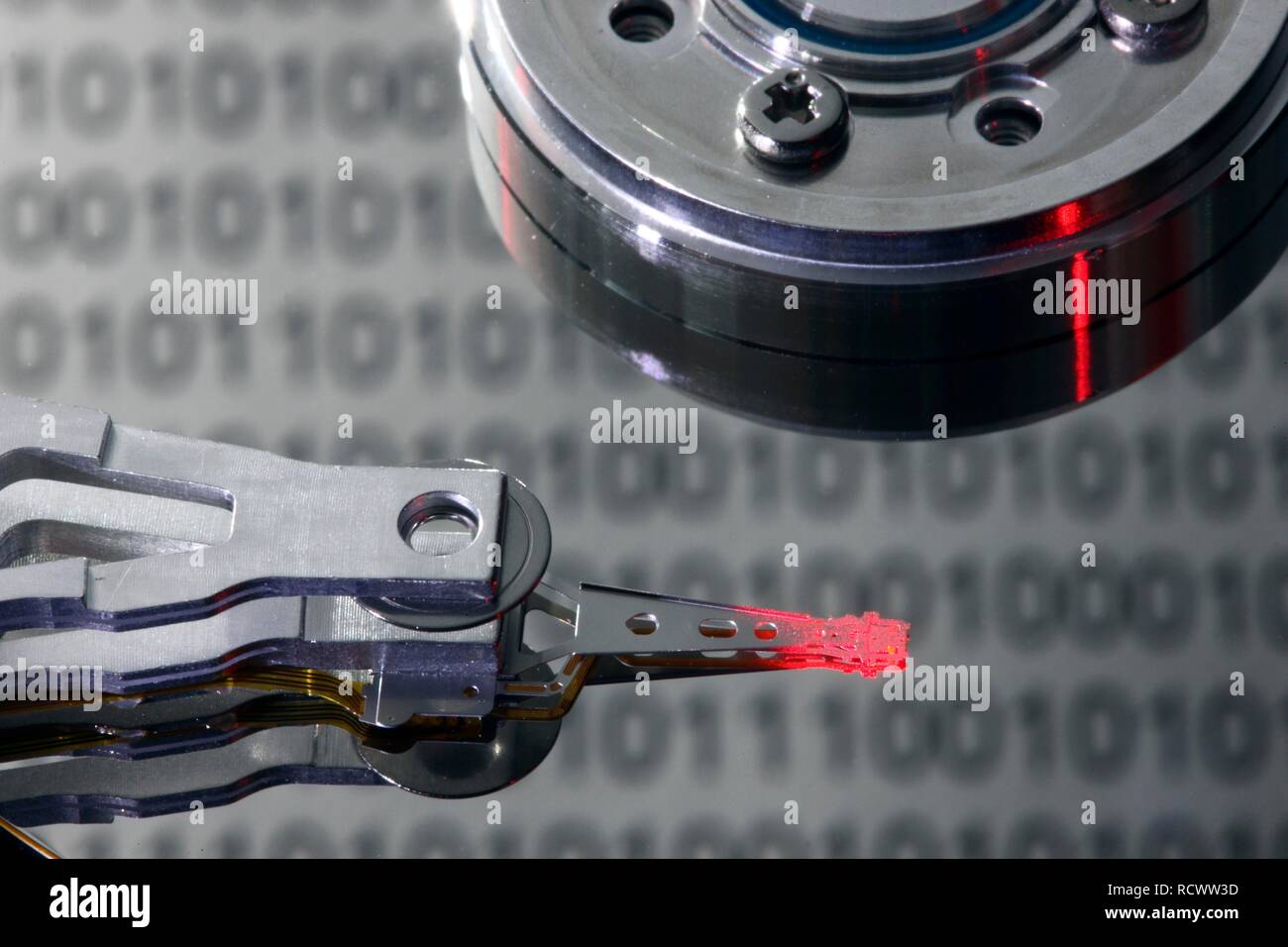 Computer hard drive, opened, read-write head on the disk, binary numbers reflected in the disc ...