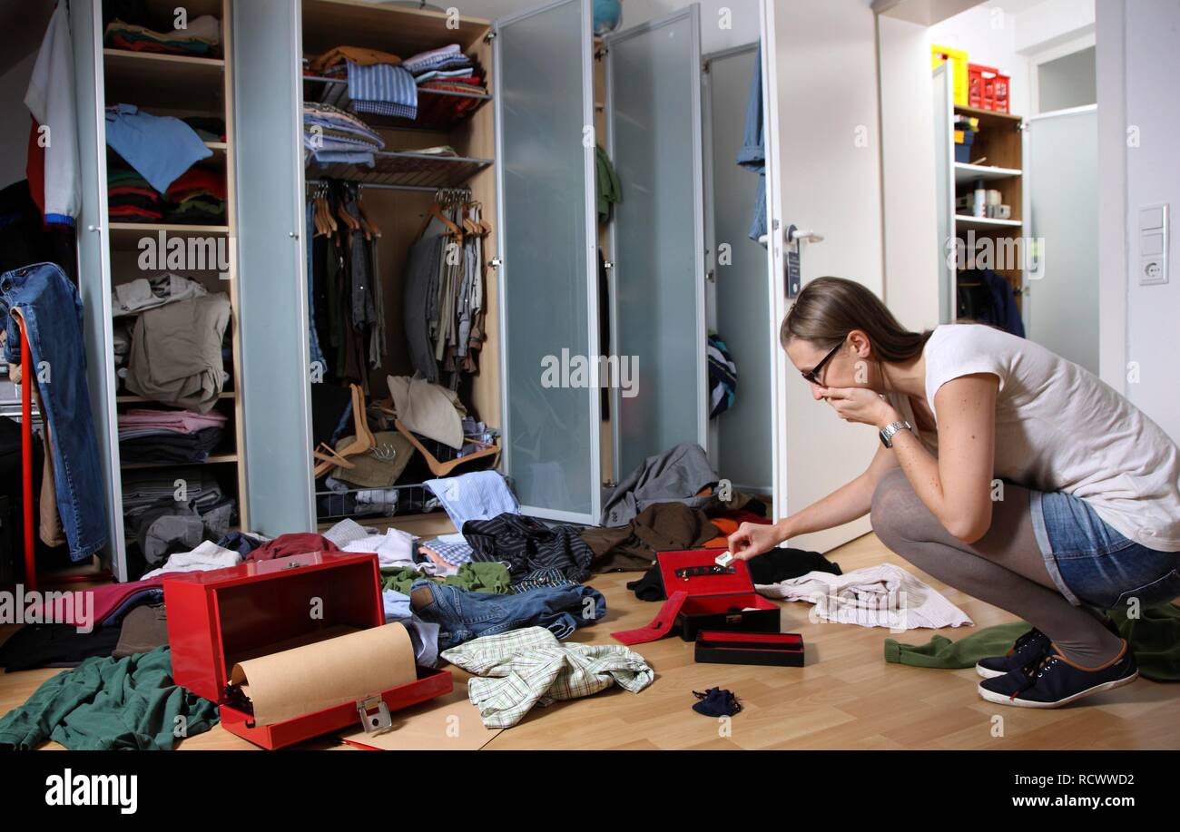 Young woman discovering the scene of a burglary, ransacked closet ...