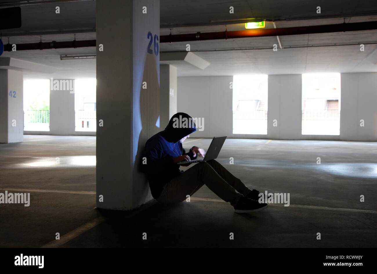 Man surfing on a laptop computer in an empty multi-storey car park ...