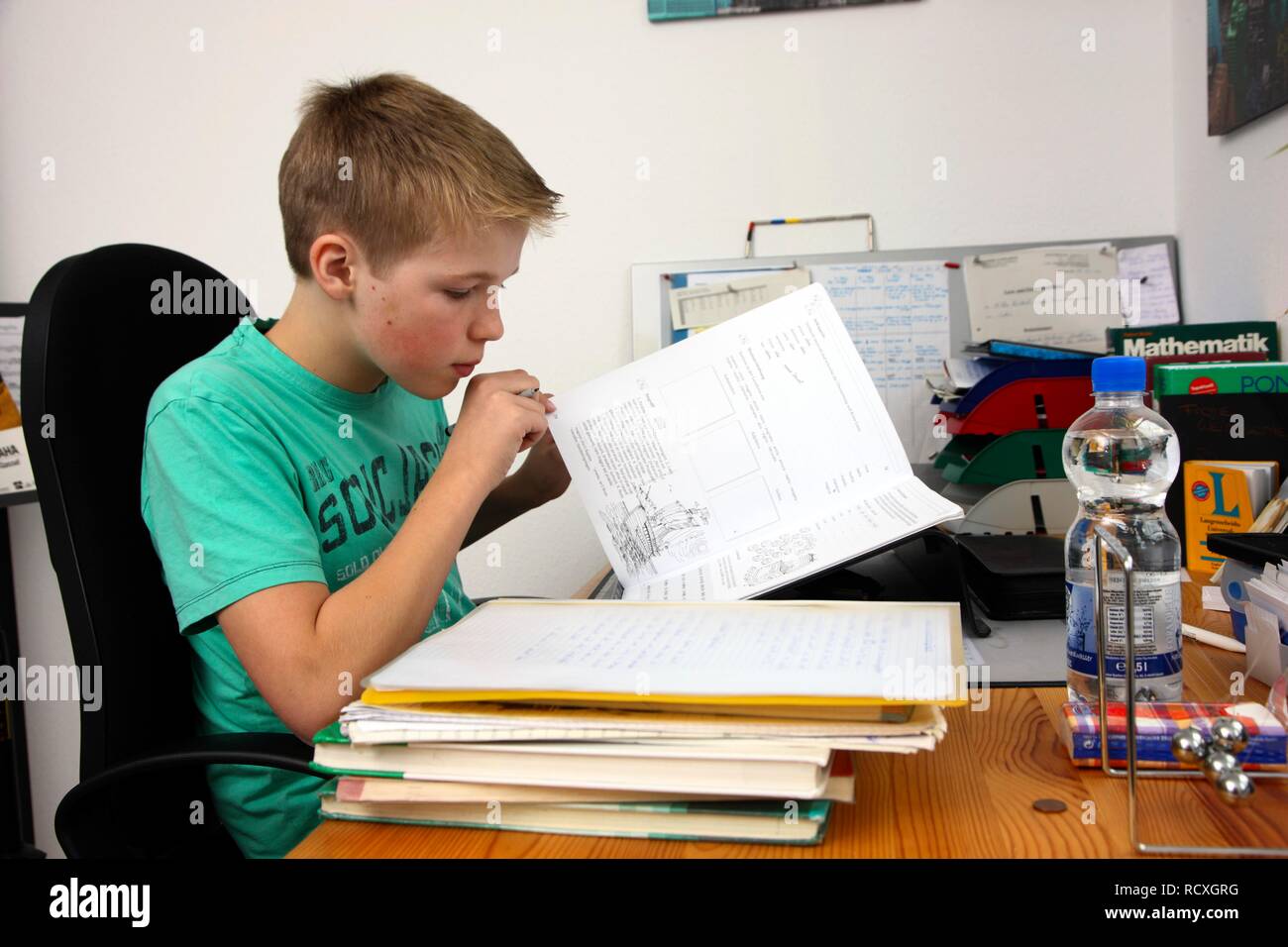 Boy, 12 years, doing his homework in his room, studying for school ...