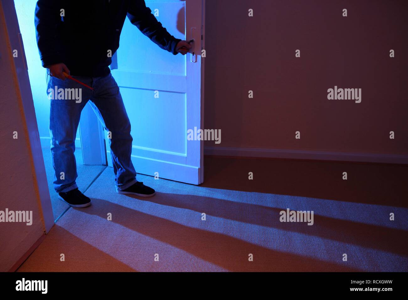 Burglar breaks open the front door and enters the apartment, symbolic ...