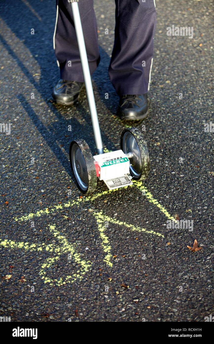 Policeman taking measurements at a crash site, measuring of the ...