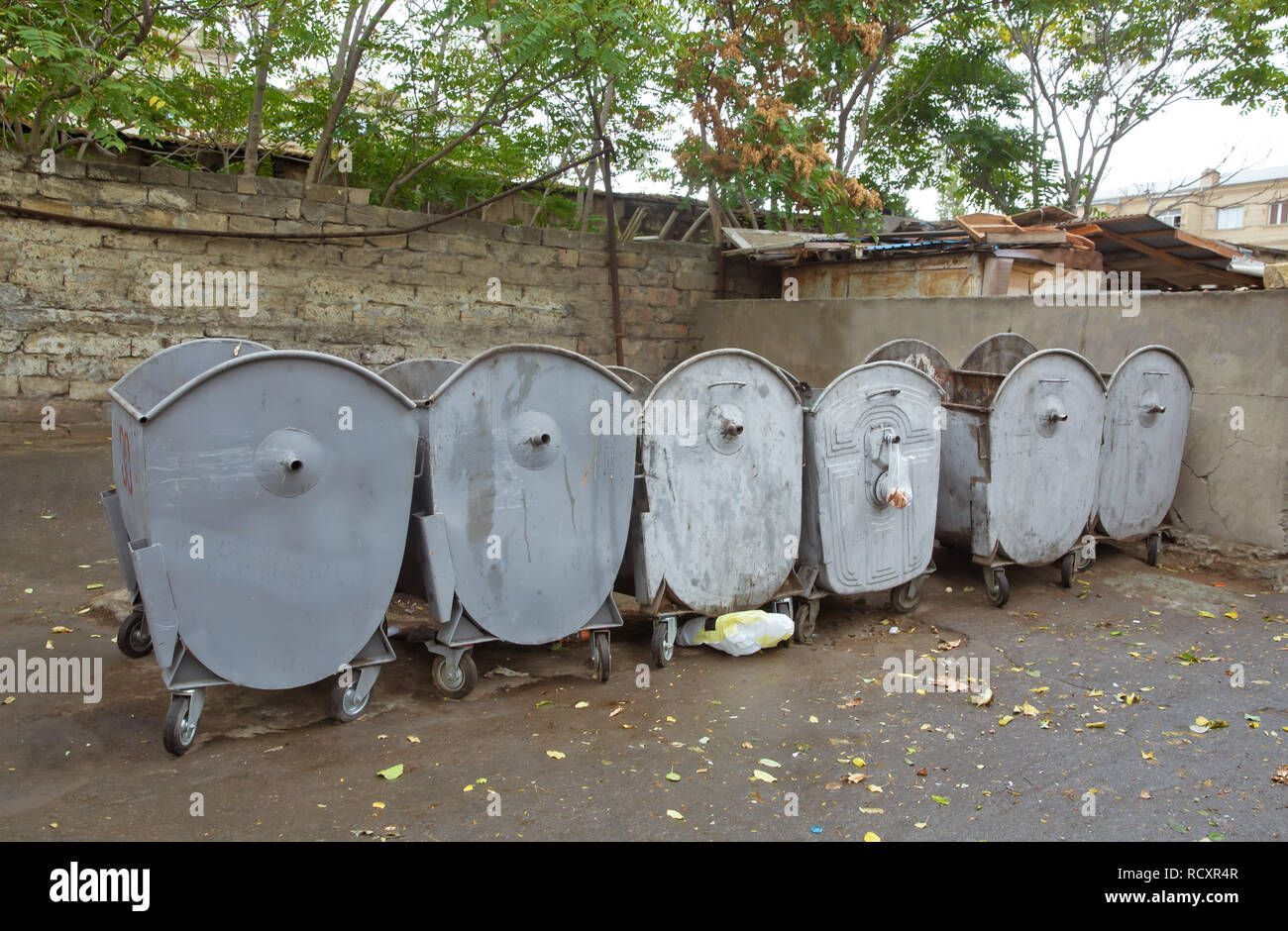 A row of gray iron garbage cans on the street. Grey garbage containers ...