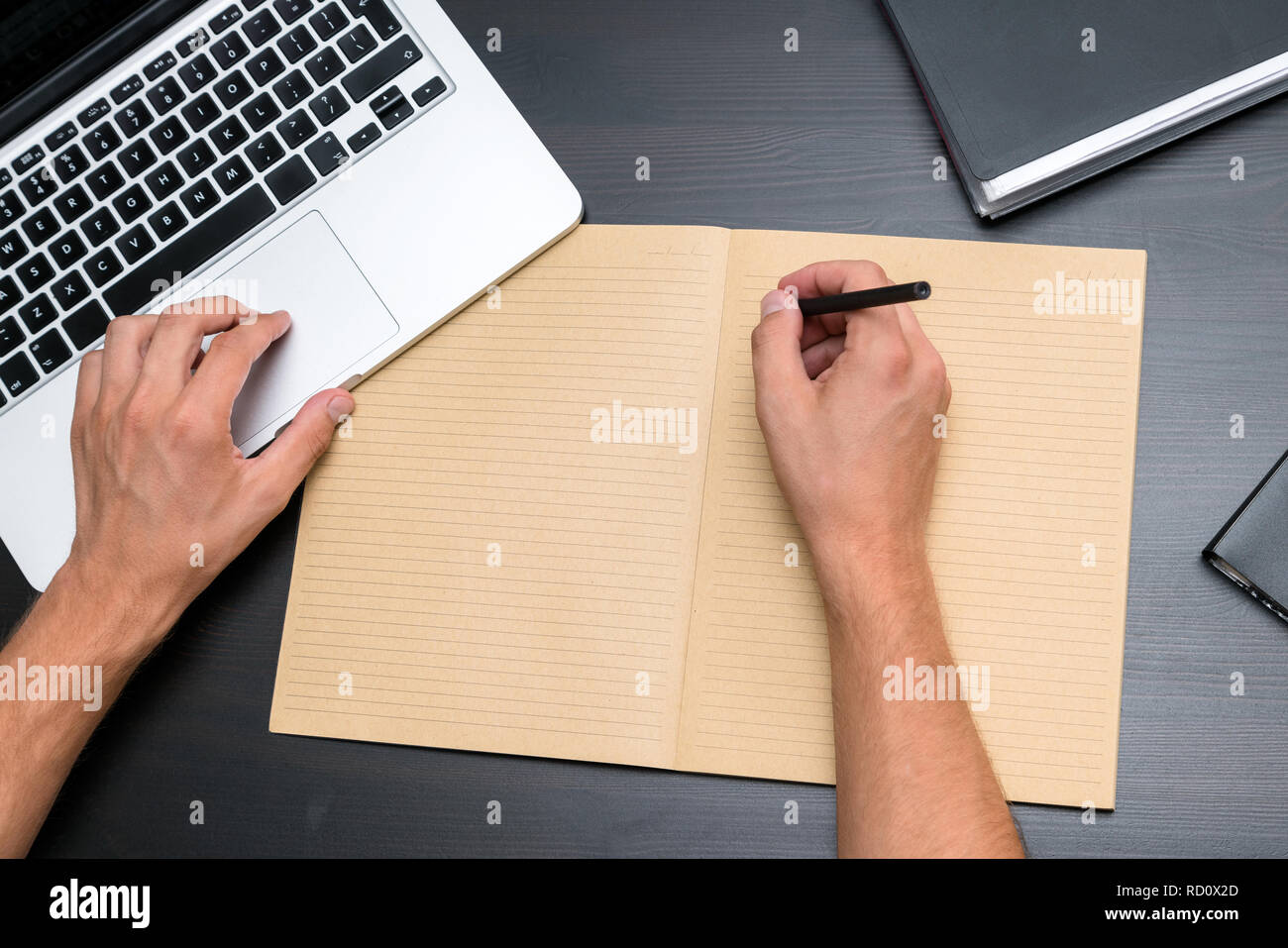 Overhead view of office table with mans hands writing with pen on blank ...