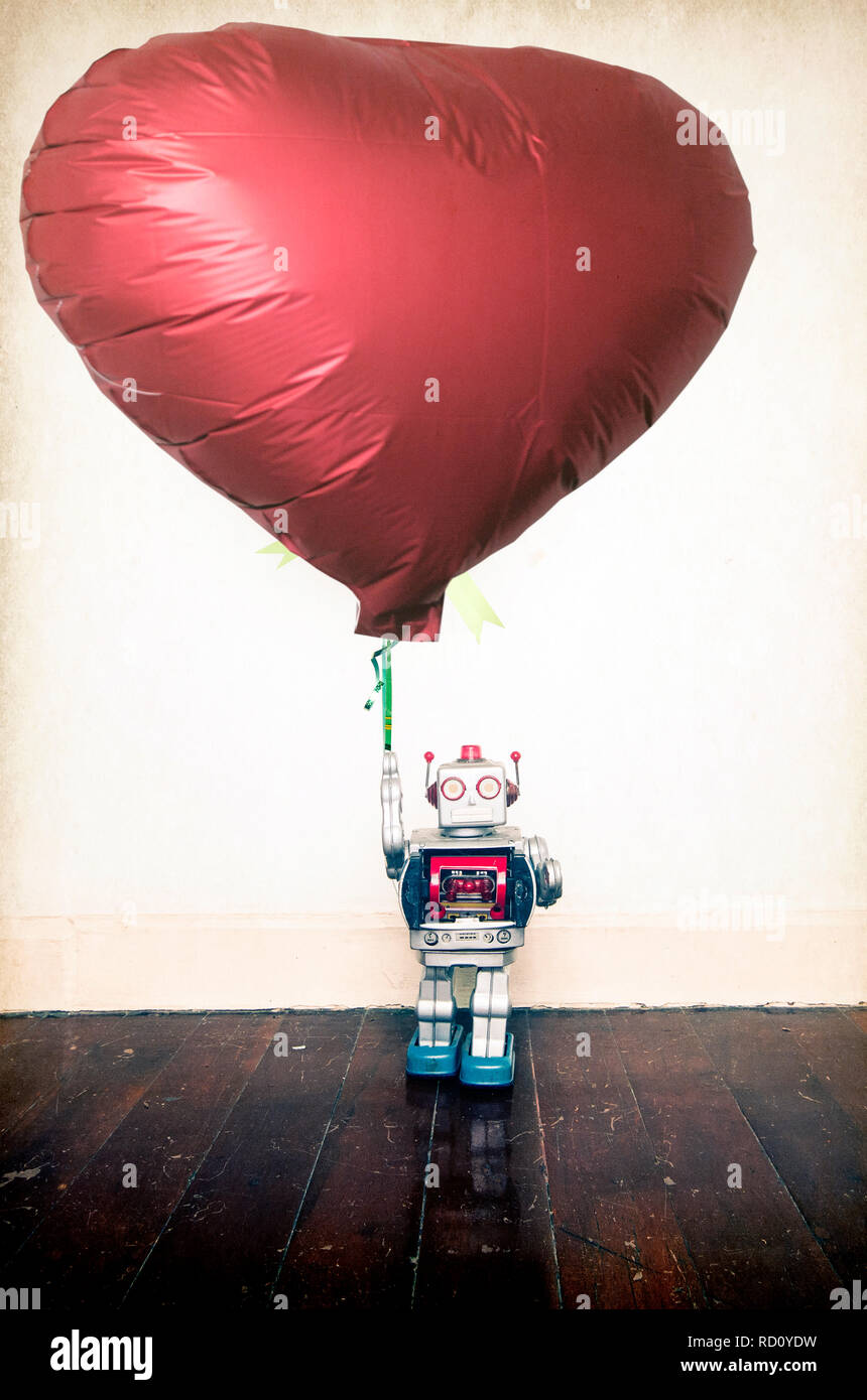 silver robot holding red balloon standing on old wooden floor copy ...