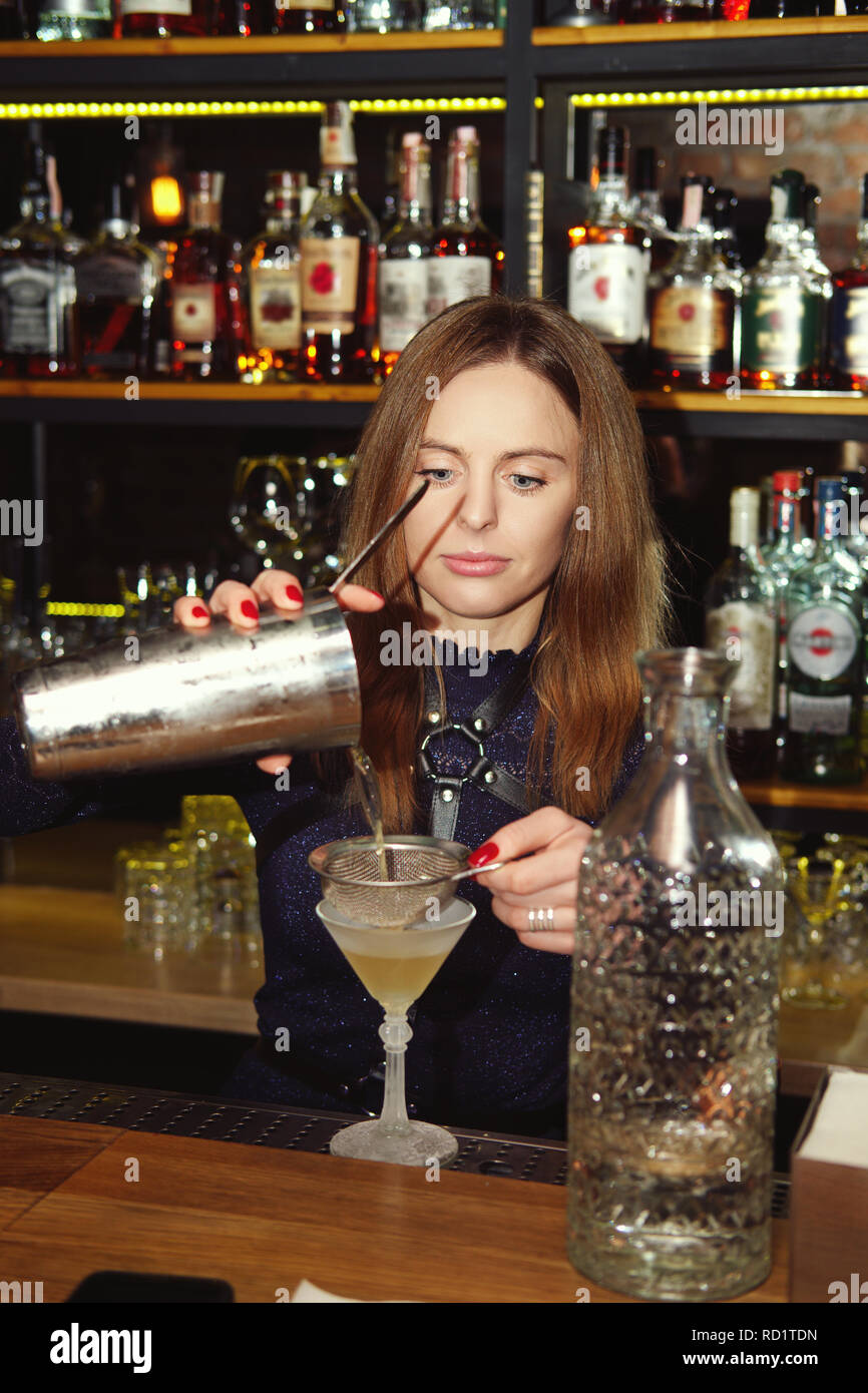 Professional bartender girl pouring a delicious cocktail into the glass ...