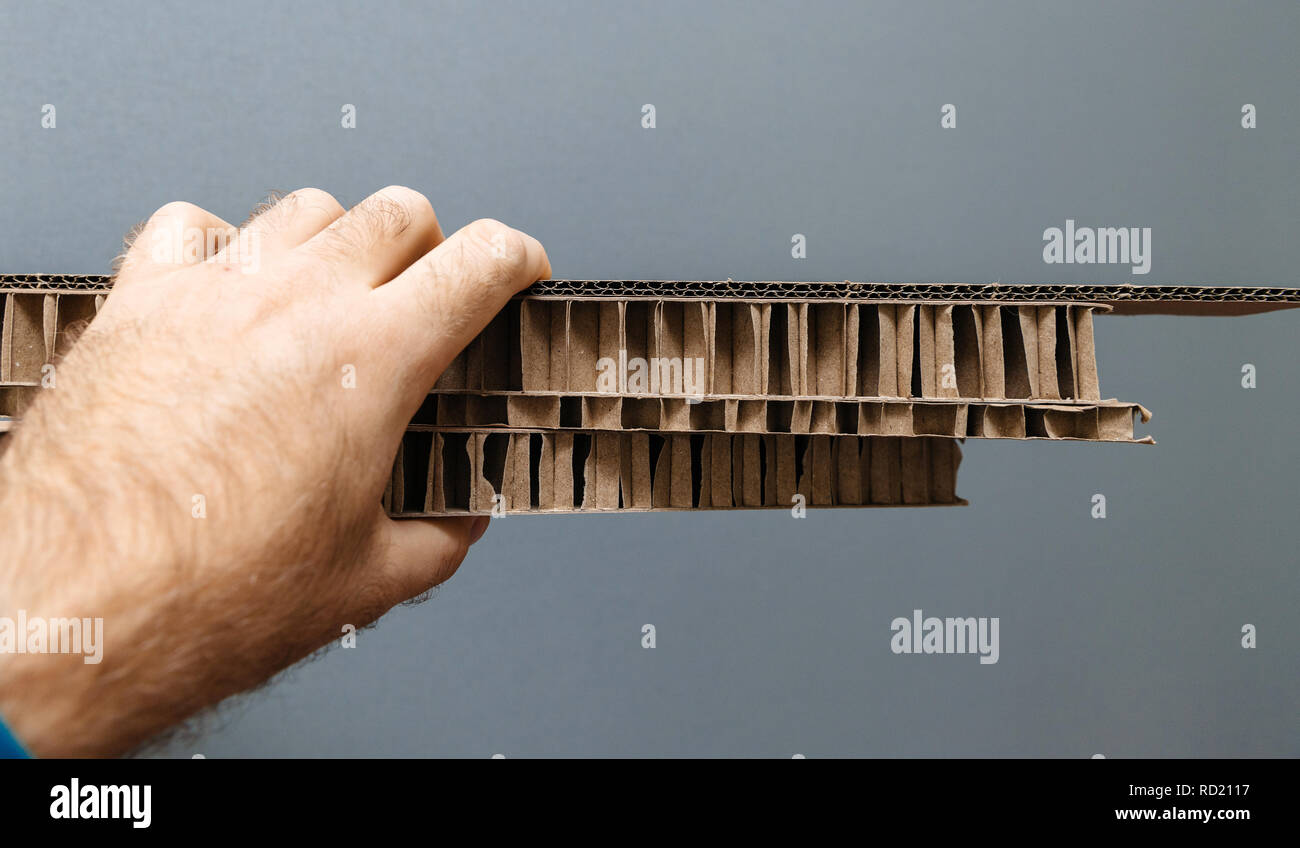 Factory worker male hand holding and inspecting against gray background ...