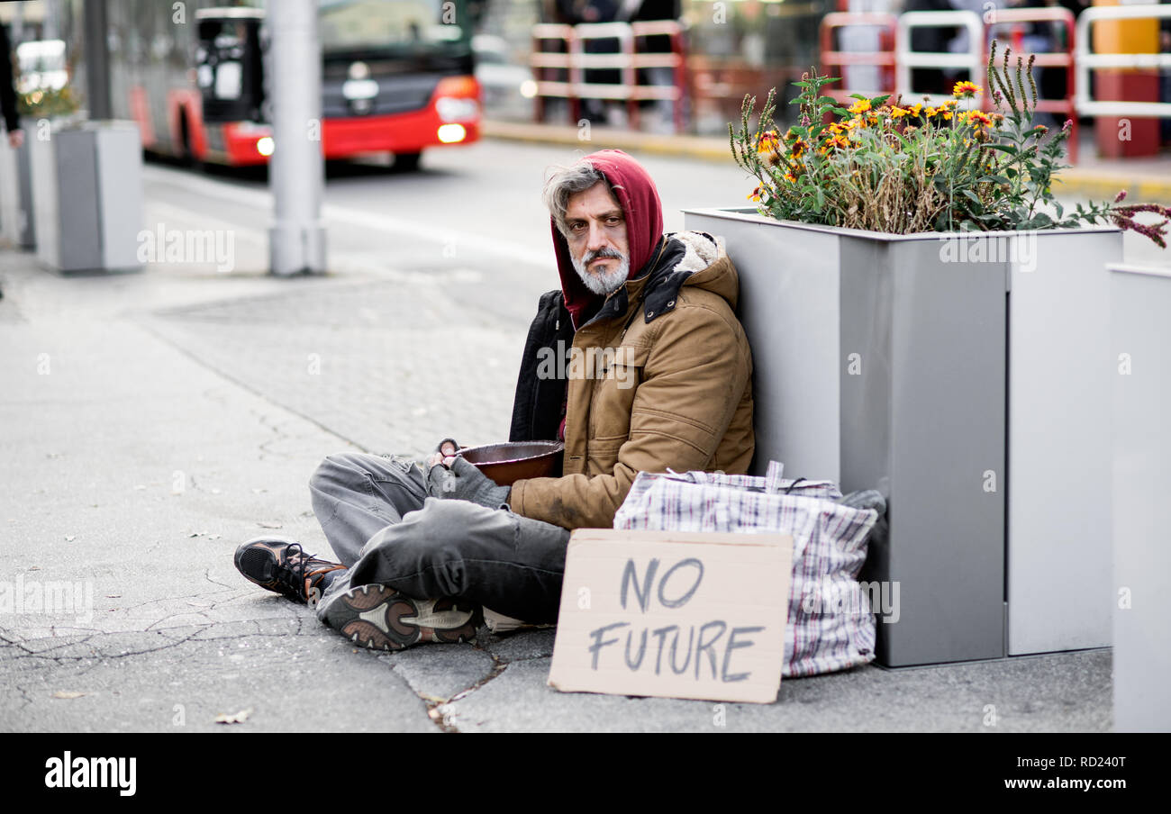 Homeless beggar man sitting outdoors in city asking for money donation ...