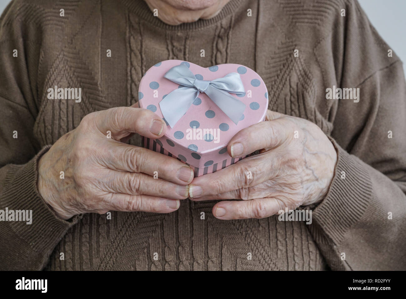 Closeup of wrinkled hands holding a heart shaped gift pack Stock Photo ...