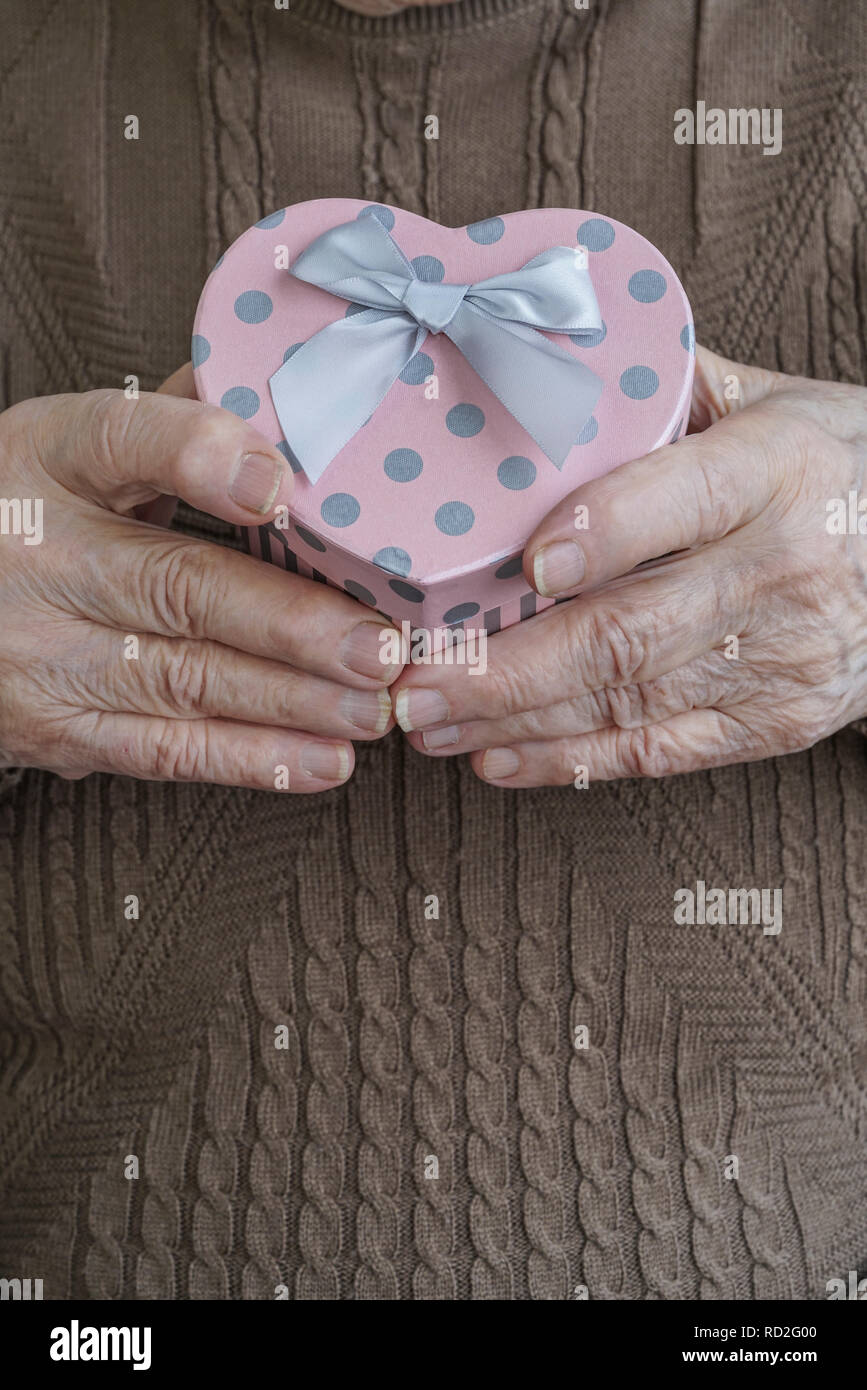 Closeup of wrinkled hands holding a heart shaped gift pack Stock Photo ...