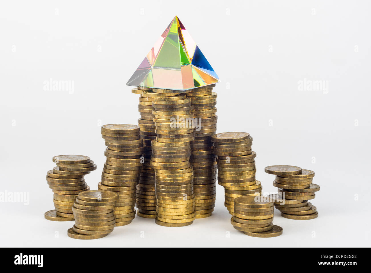 Glass pyramid on high stacks of coins Stock Photo - Alamy