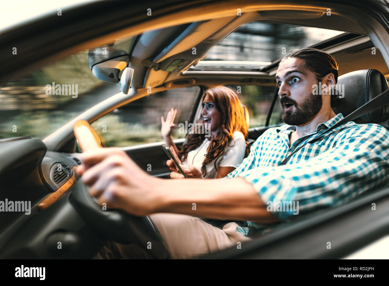 Couple in a car at sunset, with man driving fast and girl scared ...