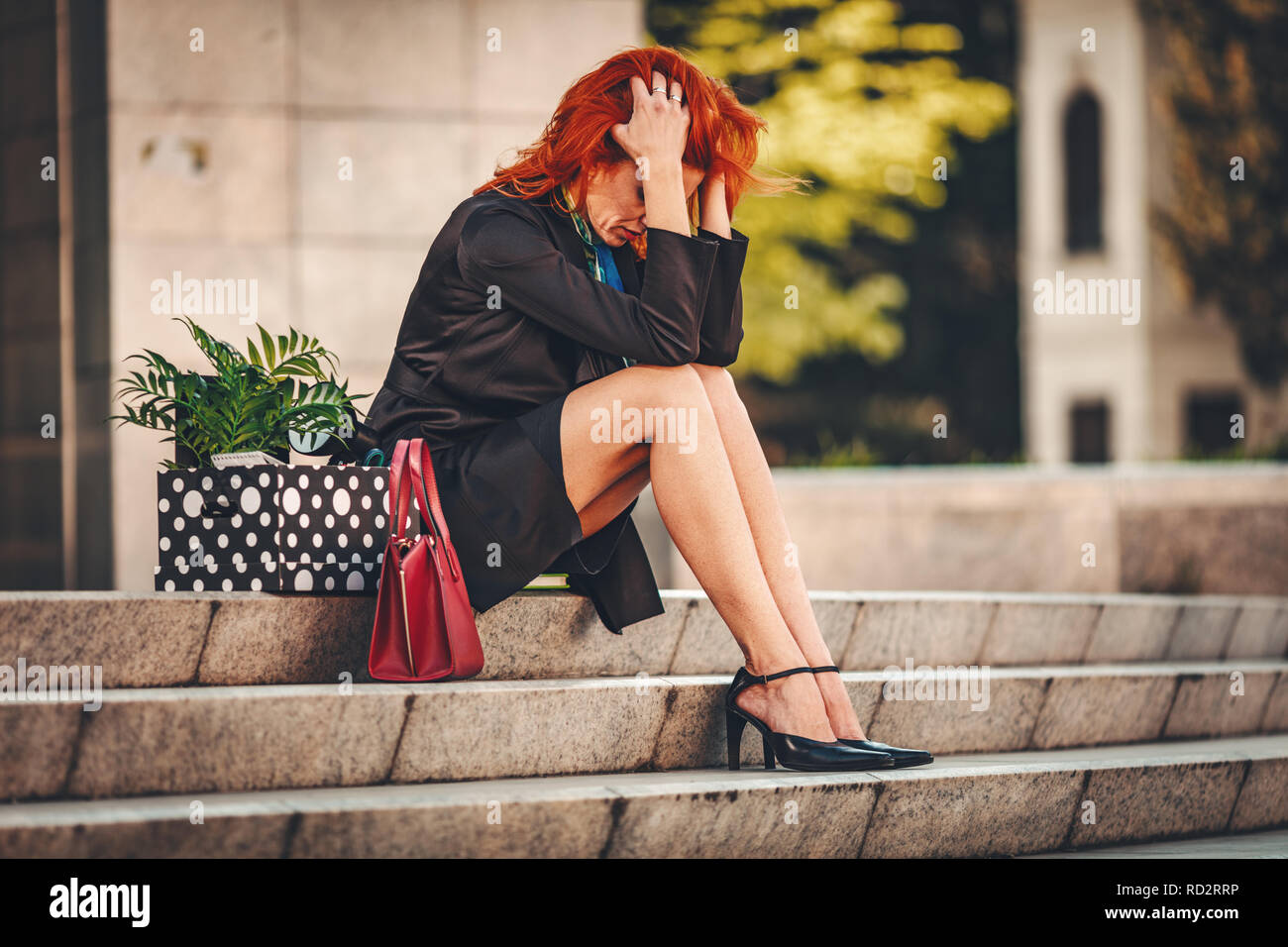 Worried business woman is crying in front of the office just after she ...