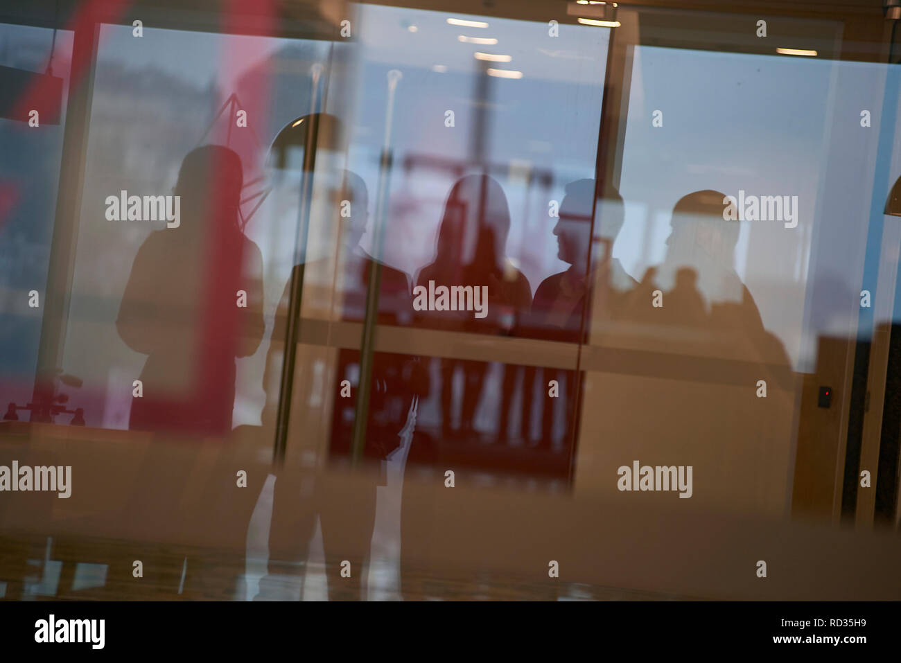 Silhouetted reflections of a group of people standing around having a ...