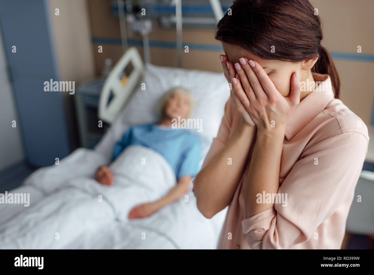 selective focus of crying daughter with sick mother in bed on ...