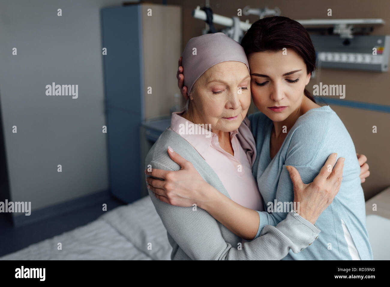 upset daughter embracing sick senior mother with cancer in hospital ...