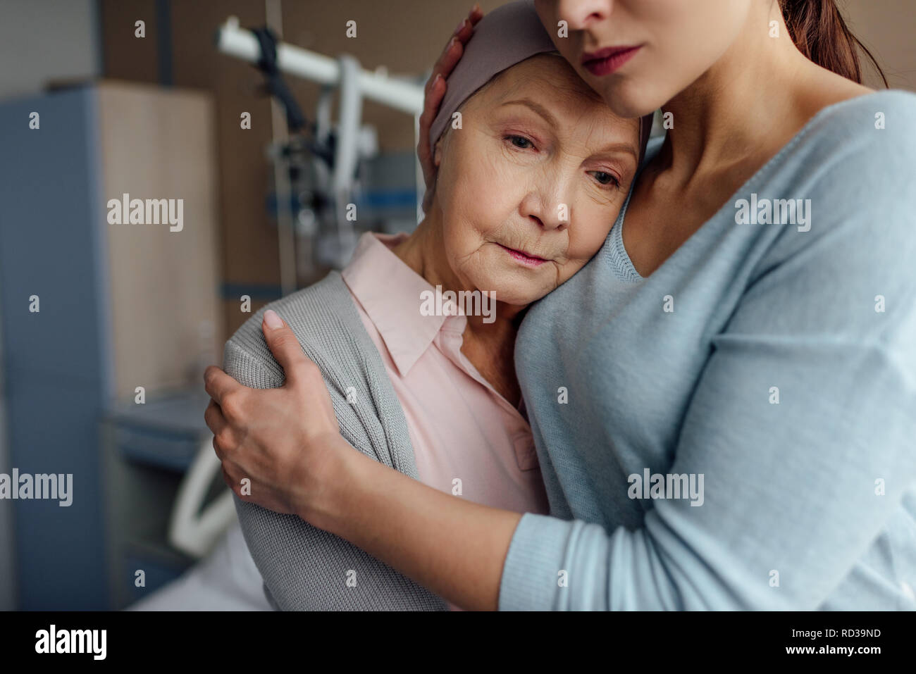 selective focus of daughter hugging sick senior mother with cancer in ...