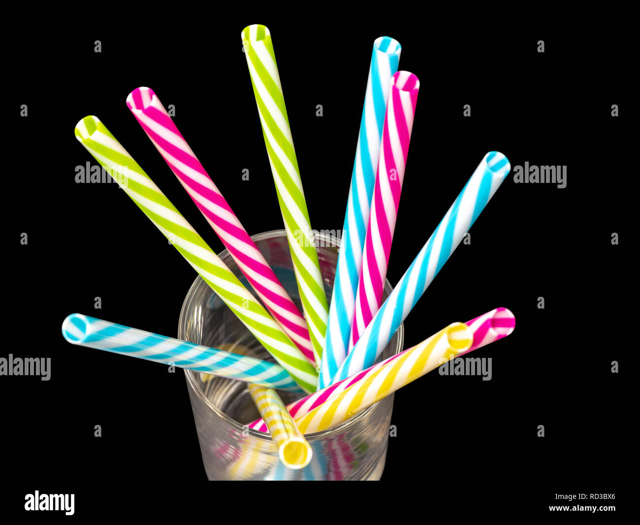 Different colored plastic drinking straws placed in a glass black ...