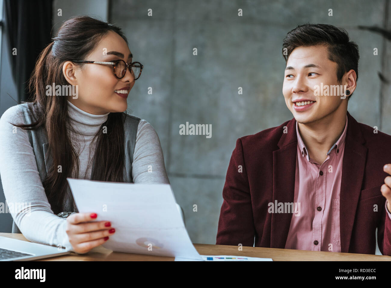 happy young coworkers smiling each other while working together in ...