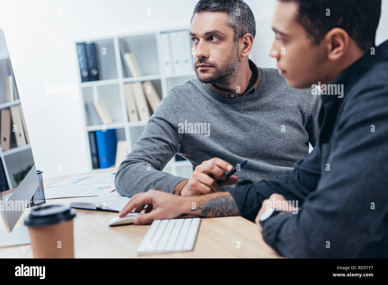 serious professional coworkers using desktop computer and working ...