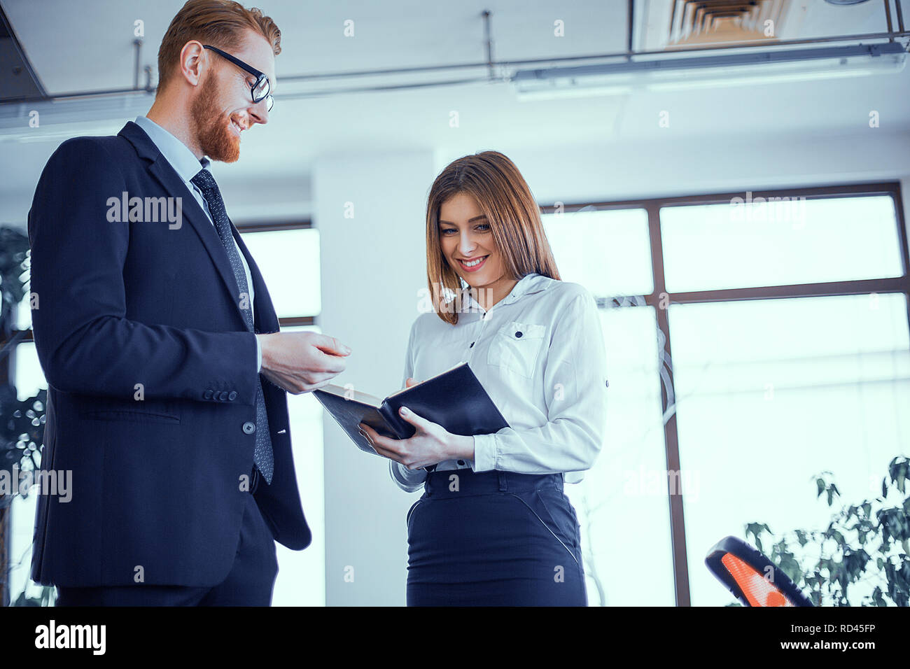 Manager and secretary with notepad in the office Stock Photo - Alamy