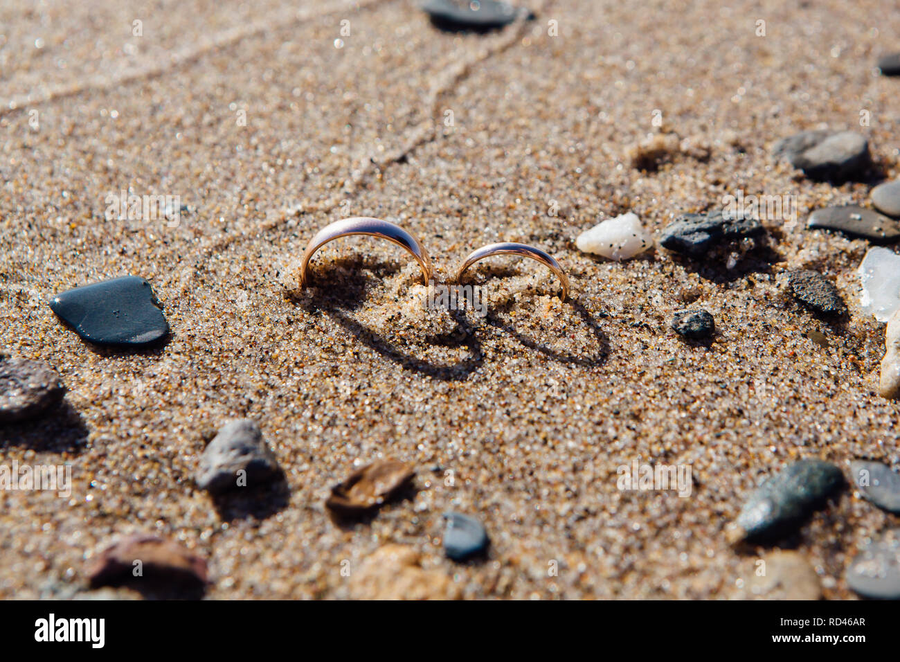 Two wedding rings in the sand on the beach. Close up Stock Photo - Alamy