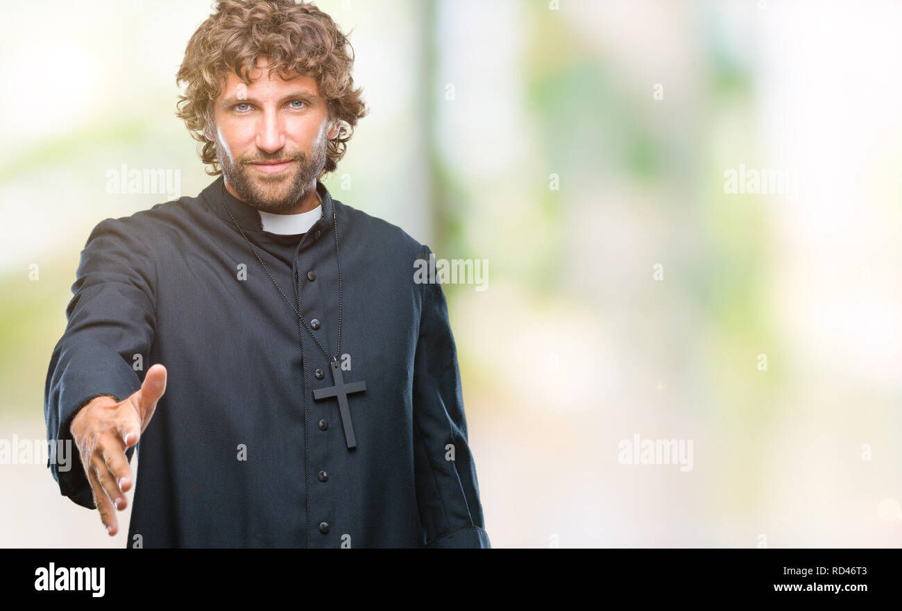 Handsome hispanic catholic priest man over isolated background smiling ...