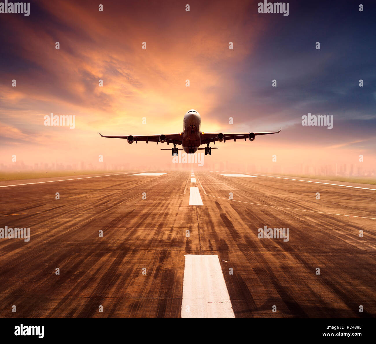 air plane flying over airport runway with city scape and sunset sky ...