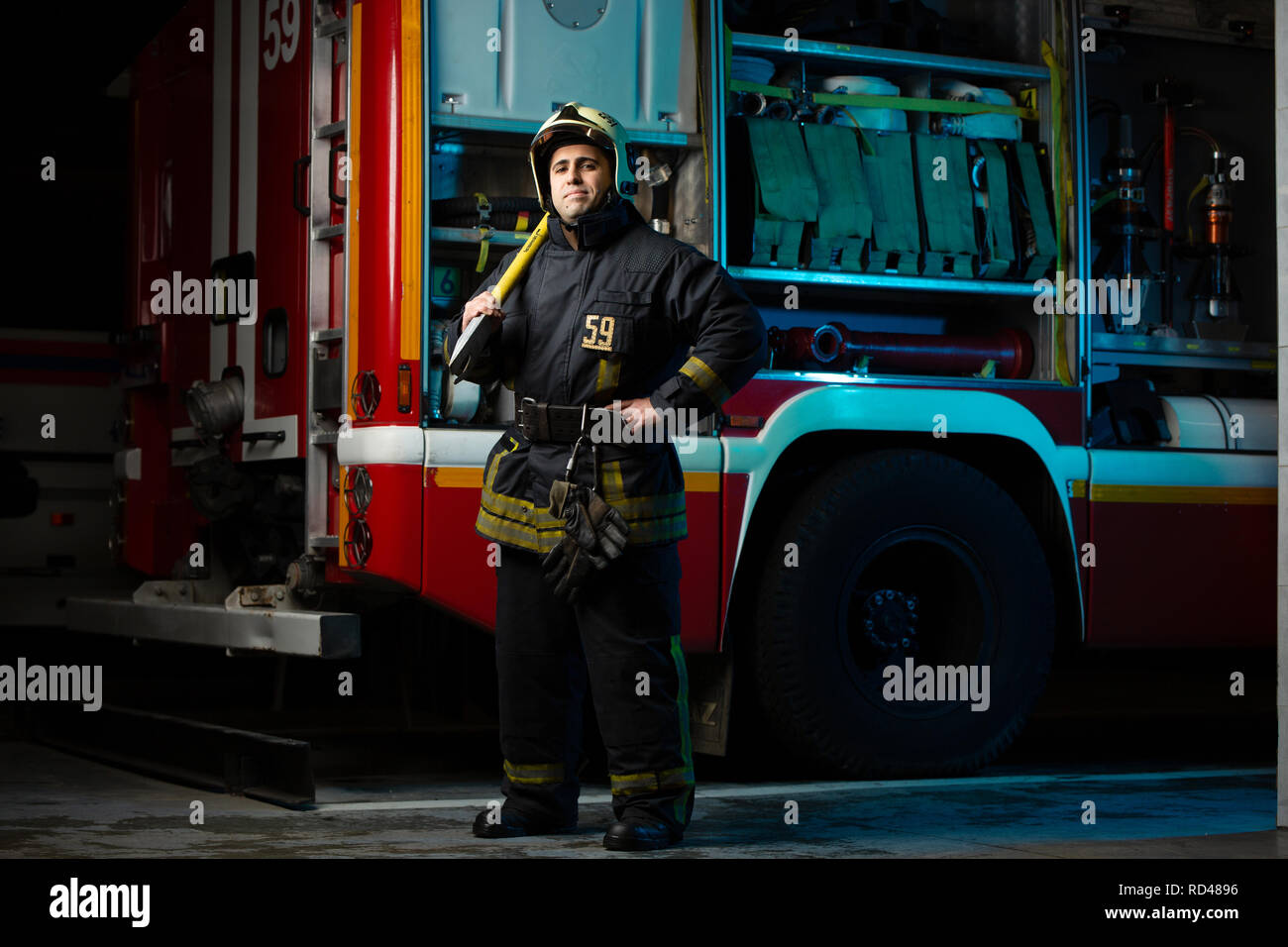 Full-length photo of firefighter man with pick near fire truck Stock ...