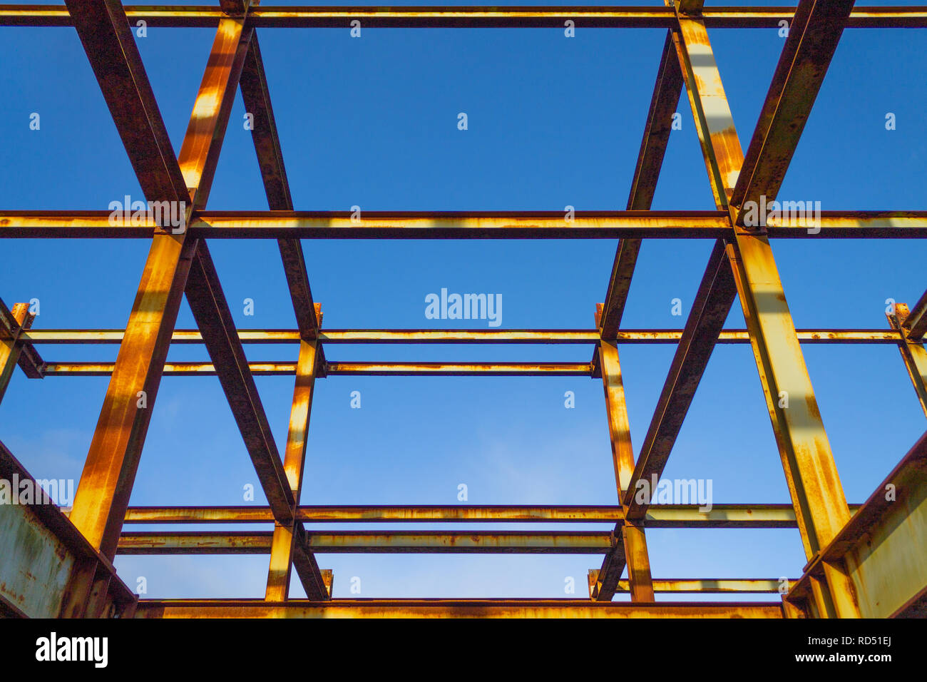 rusting rolled steel joist skeleton of a building outlined against a ...