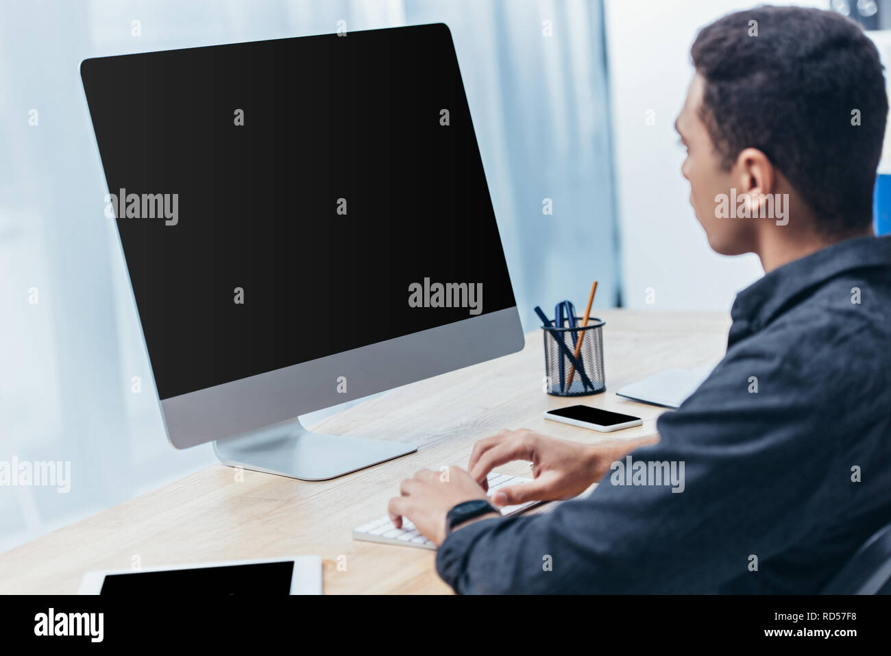 young businessman using desktop computer with blank screen in office ...