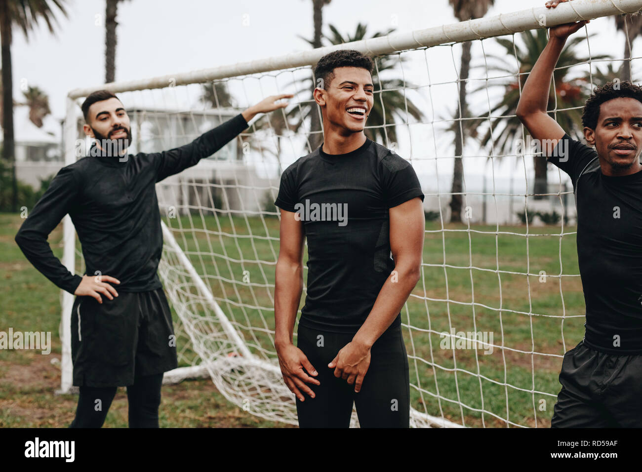 Three footballers standing at the goalpost taking a break during a ...