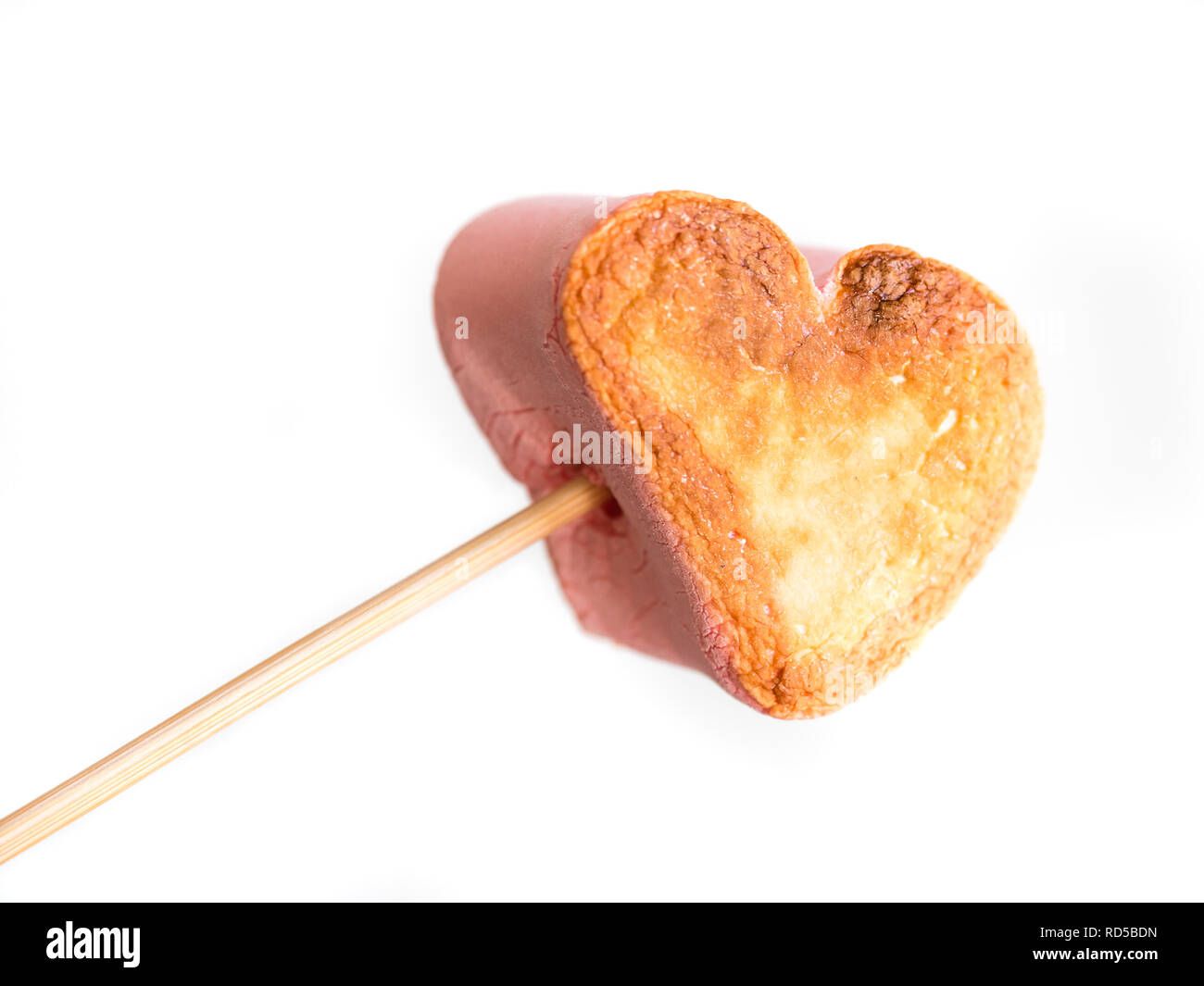 roasted heart form marshmallows on a skewer in female hand on white ...