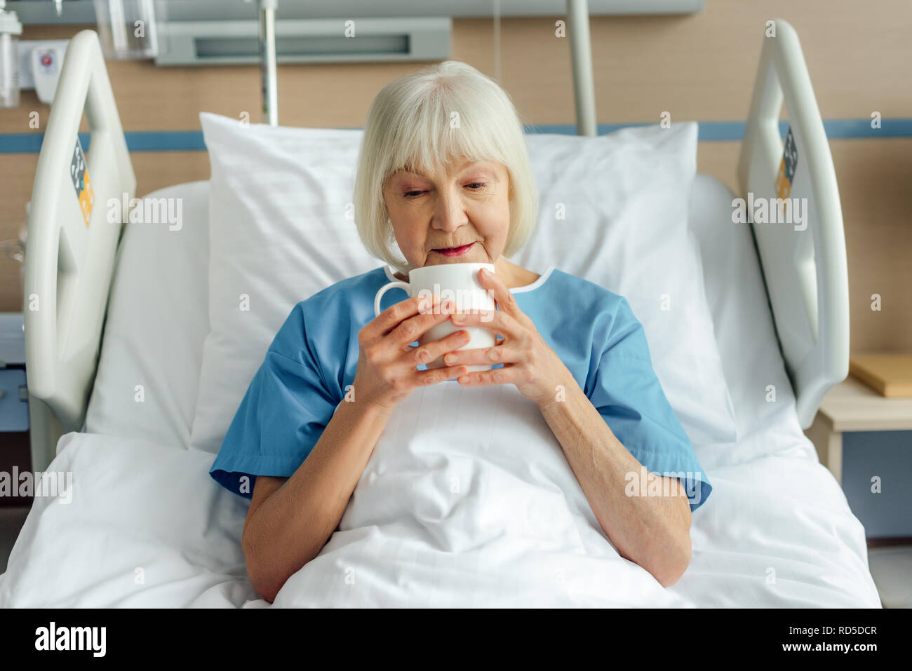senior woman lying in bed and drinking tea in hospital Stock Photo - Alamy