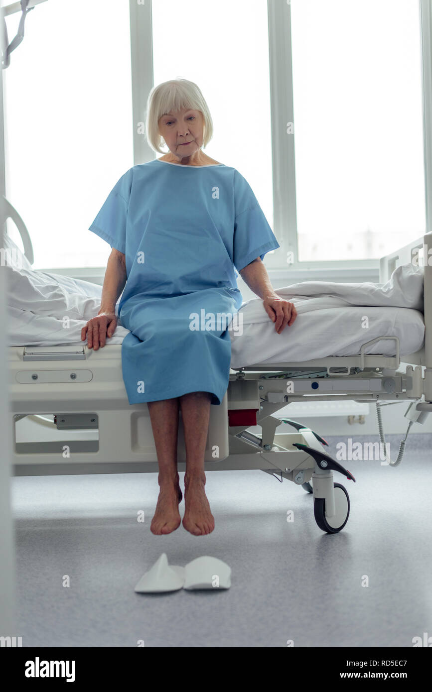 sad senior woman sitting on bed in hospital ward Stock Photo - Alamy