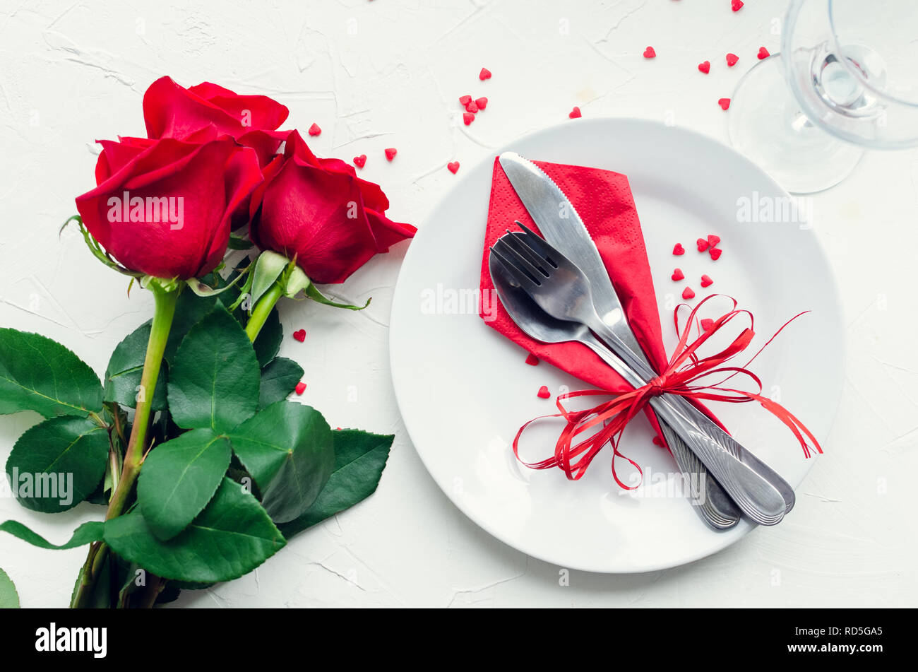Valentine's Day romantic tabble setting with red roses, plates, cutlery ...