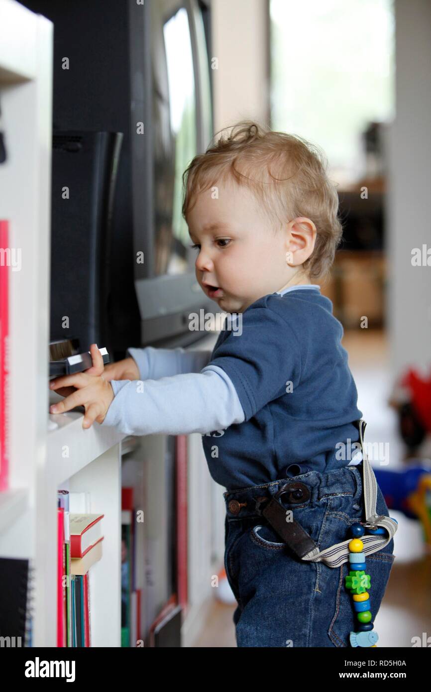 Little boy, 1 year, exploring a DVD player Stock Photo - Alamy