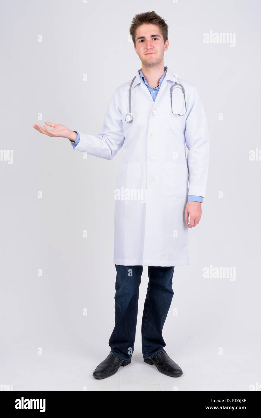 Full body shot of young handsome man doctor showing something Stock ...