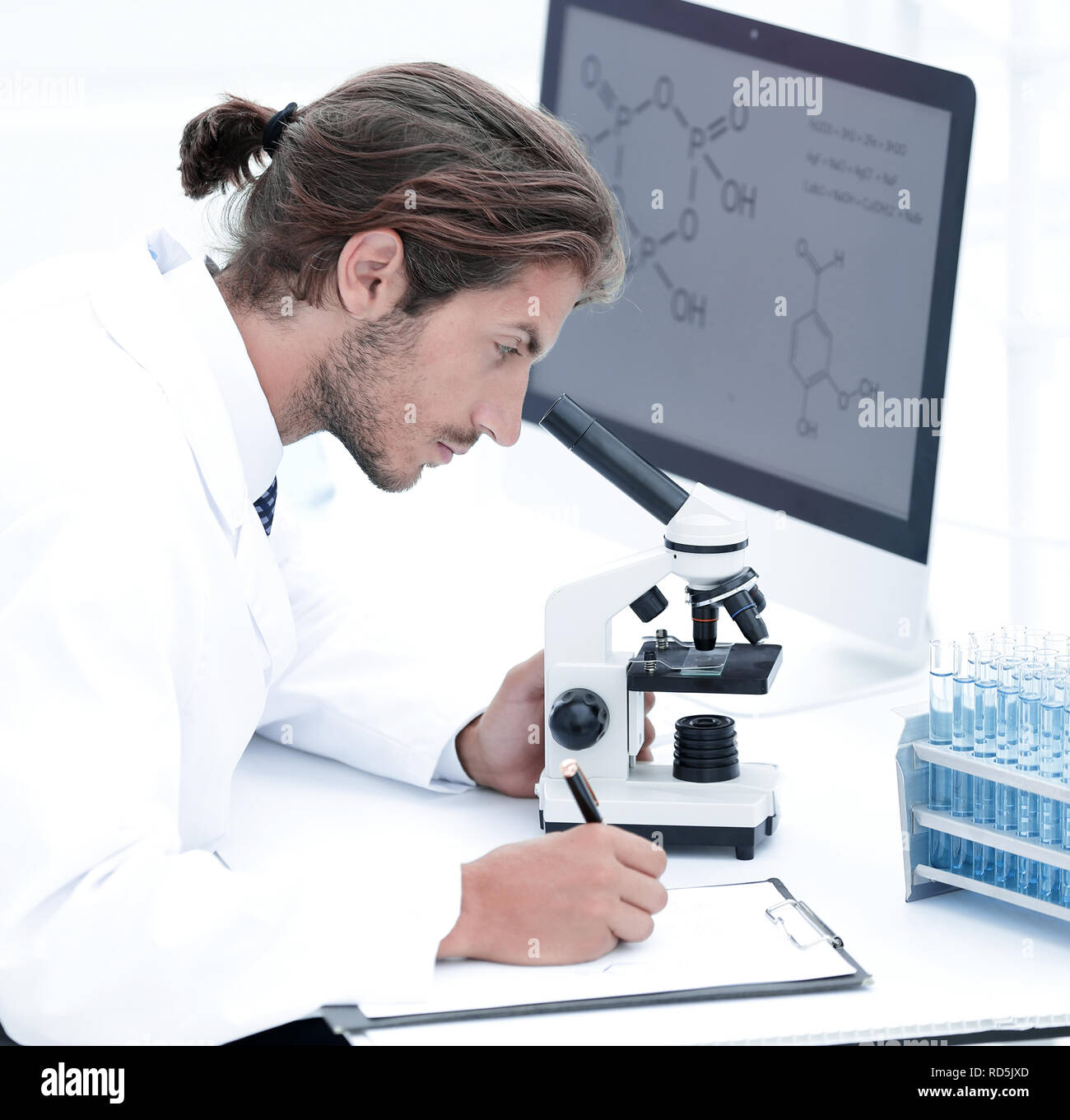 Laboratory worker sitting by table with microscope Stock Photo - Alamy