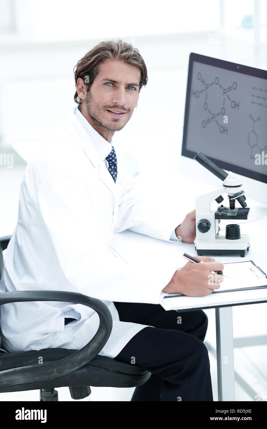 Laboratory worker sitting by table with microscope Stock Photo - Alamy