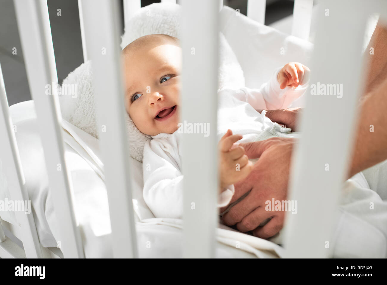 cropped view of dad putting cheerful baby into baby crib Stock Photo ...