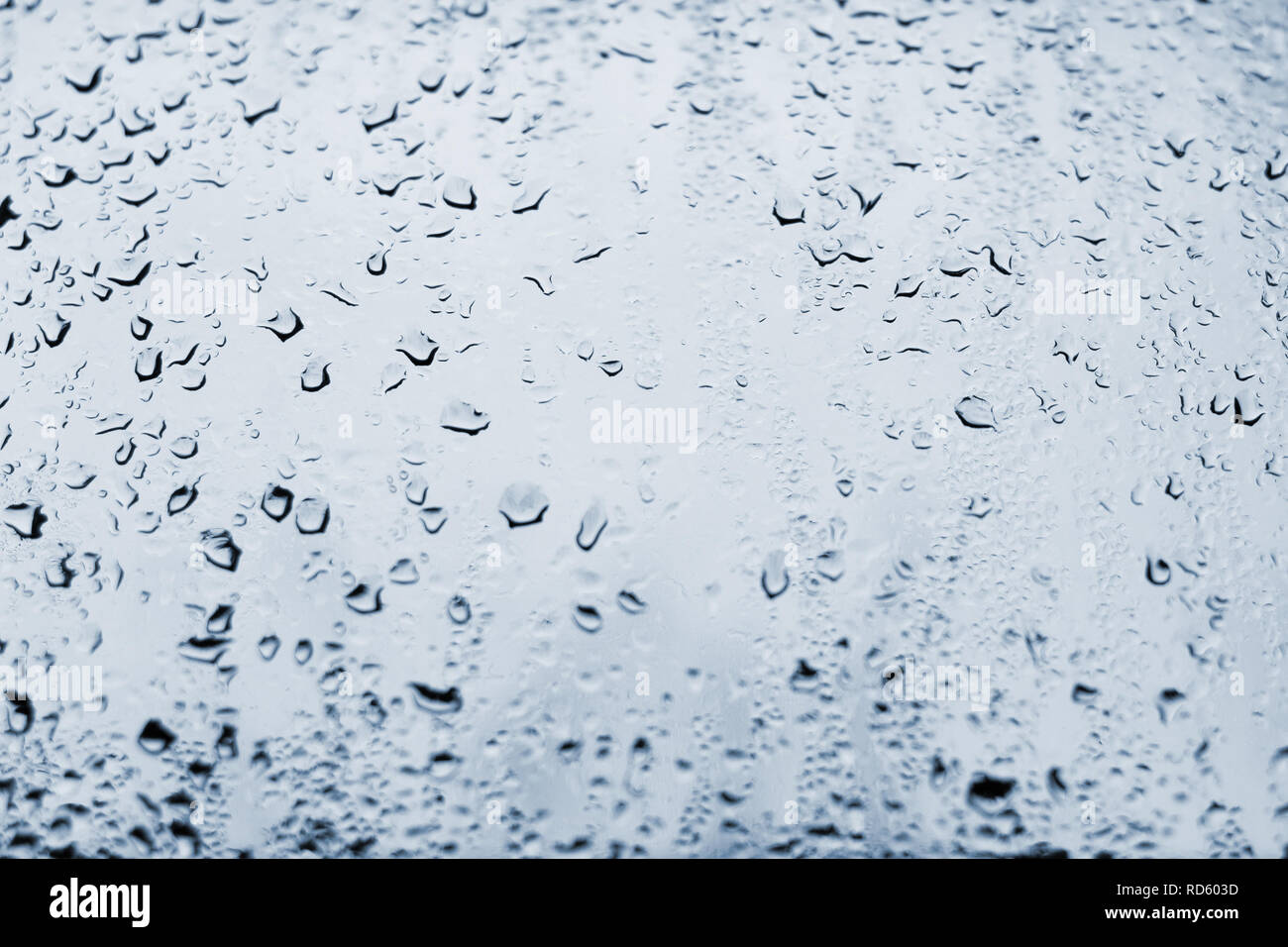 High contrast photo of drops of rain on a window glass with light pale ...