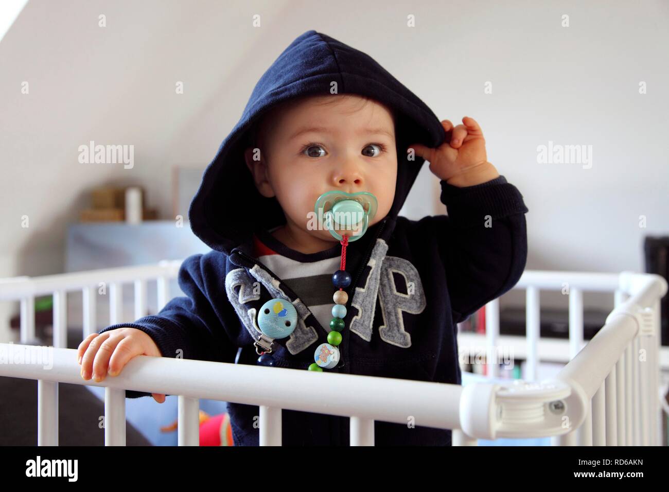 Little boy, 10 months, in the cot with pacifier and hoodie Stock Photo ...