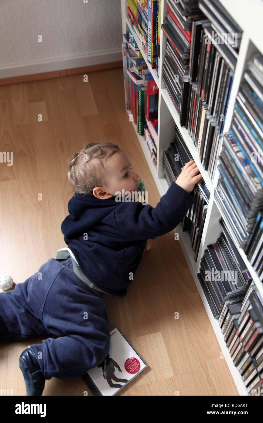 Little boy, 10 months, taking CDs off the shelf Stock Photo - Alamy