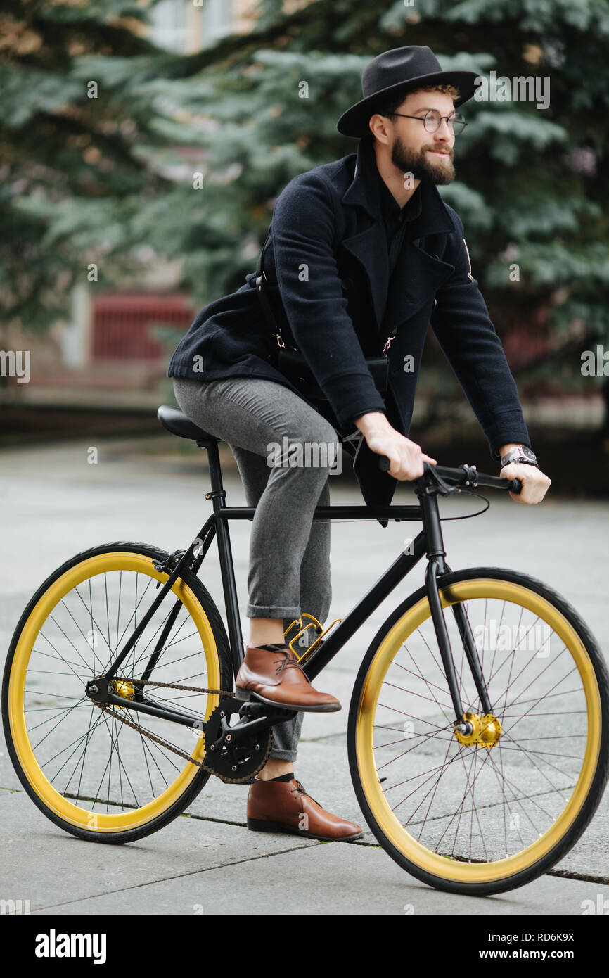 Full length photo of smiling young bearded man riding a bike on the ...