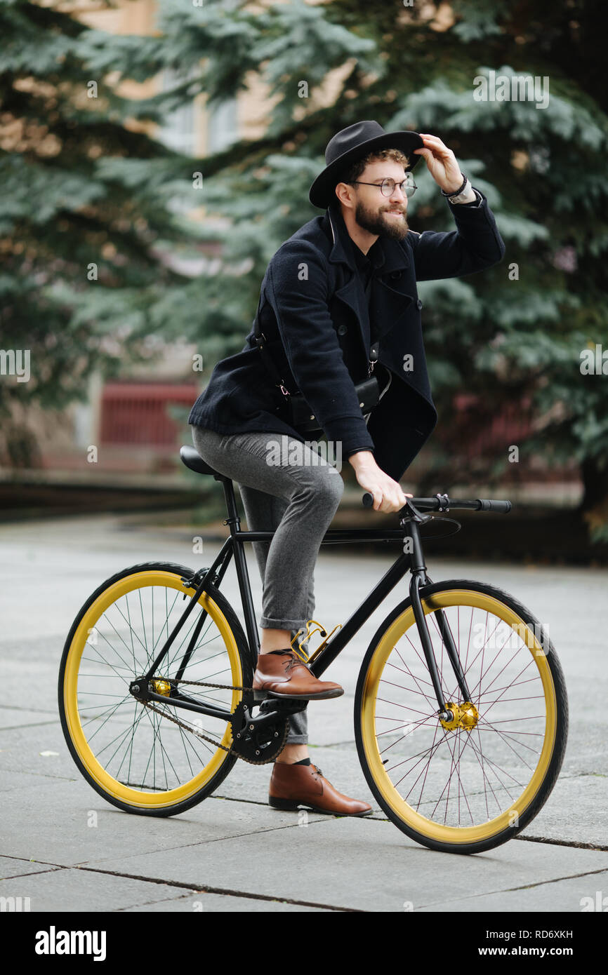 Full length photo of smiling young bearded man riding a bike on the ...