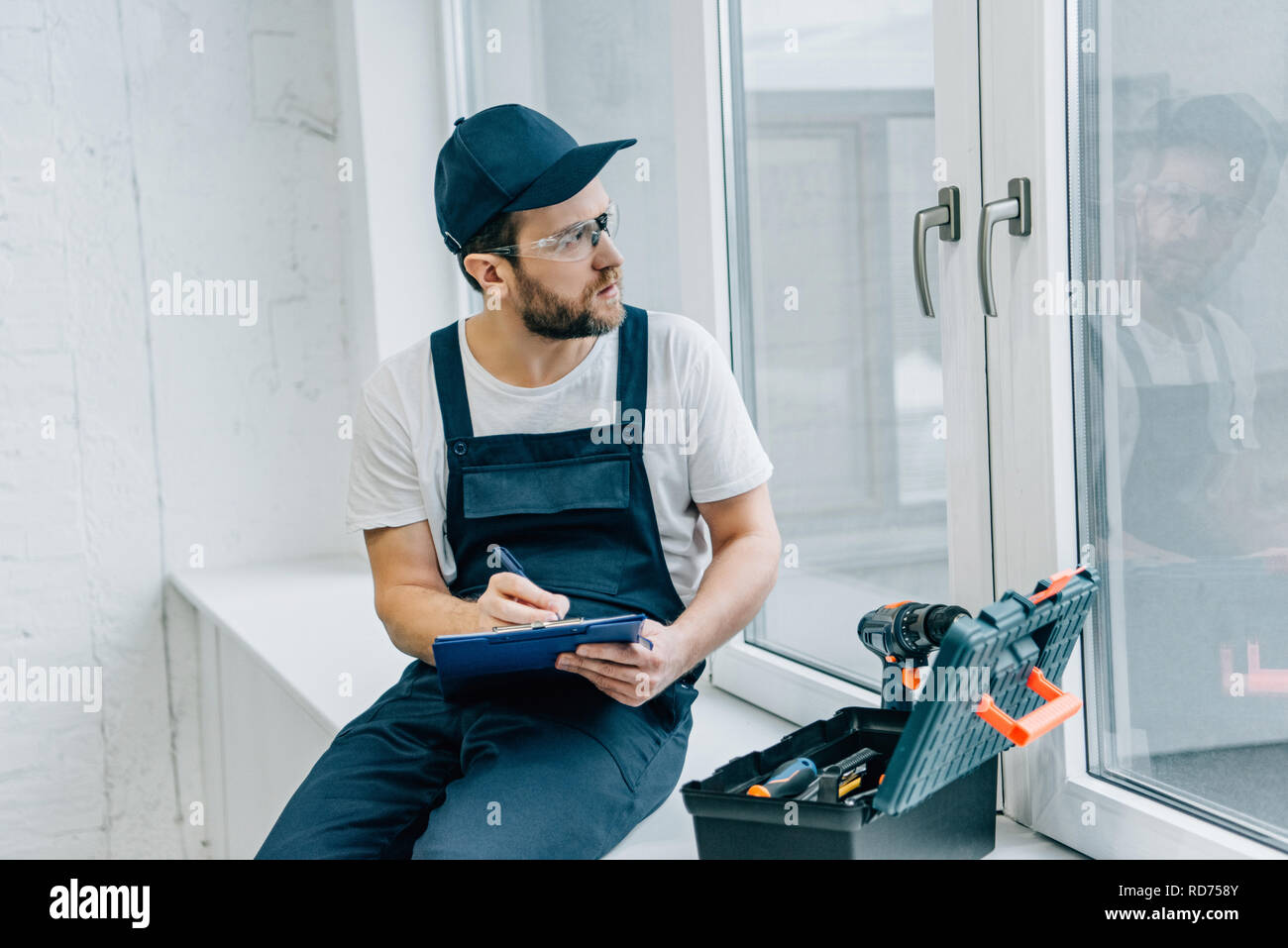 craftsman in goggles writing in clipboard and checking window Stock ...