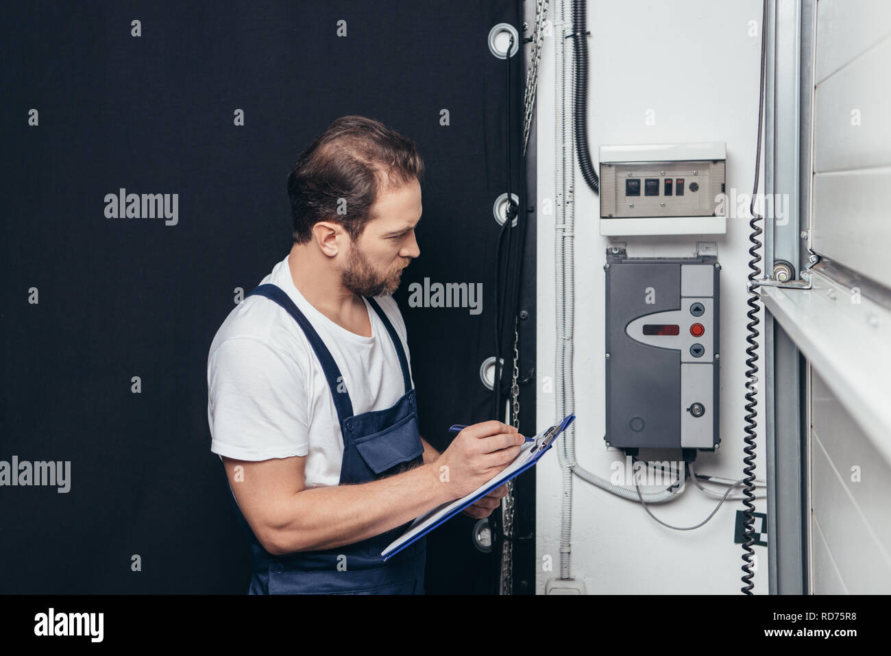 male electrician writing in clipboard and checking electrical box Stock ...