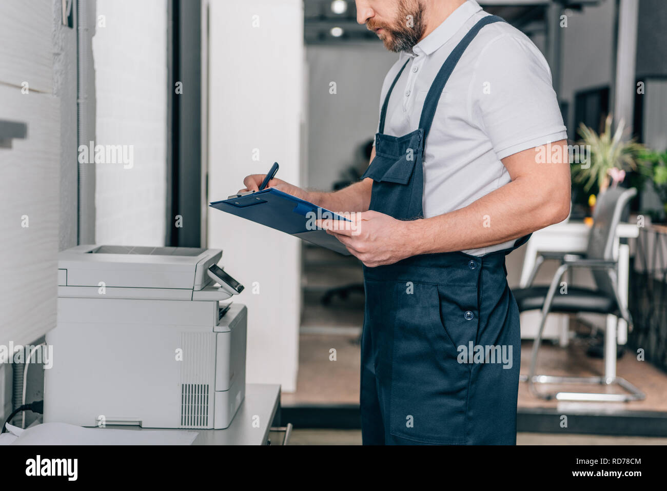 partial view of craftsman checking copy machine and writing in ...