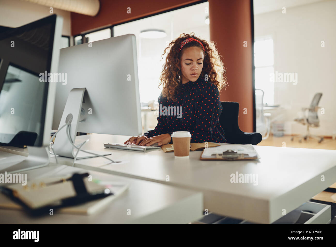 Young businesswoman sitting alone at her desk in an empty office ...
